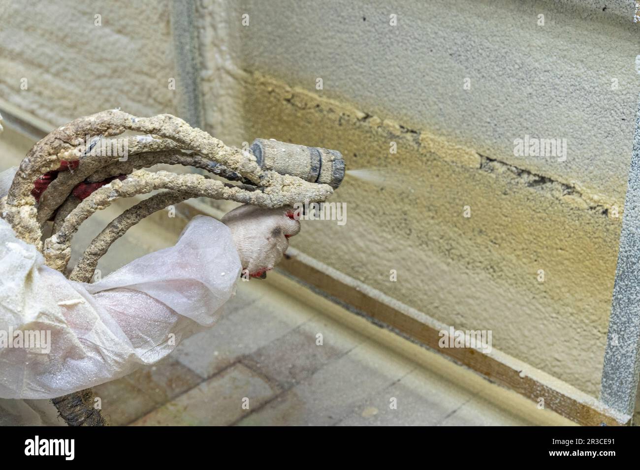worker in a protective suit insulates the walls with polyurethane foam ...