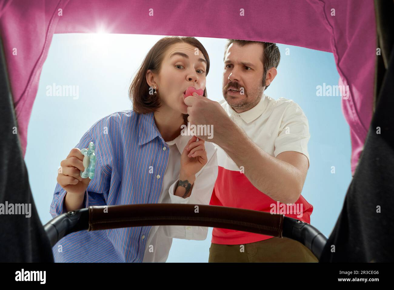 Funny, happy young man and woman, looking inside baby stroller, playing ...