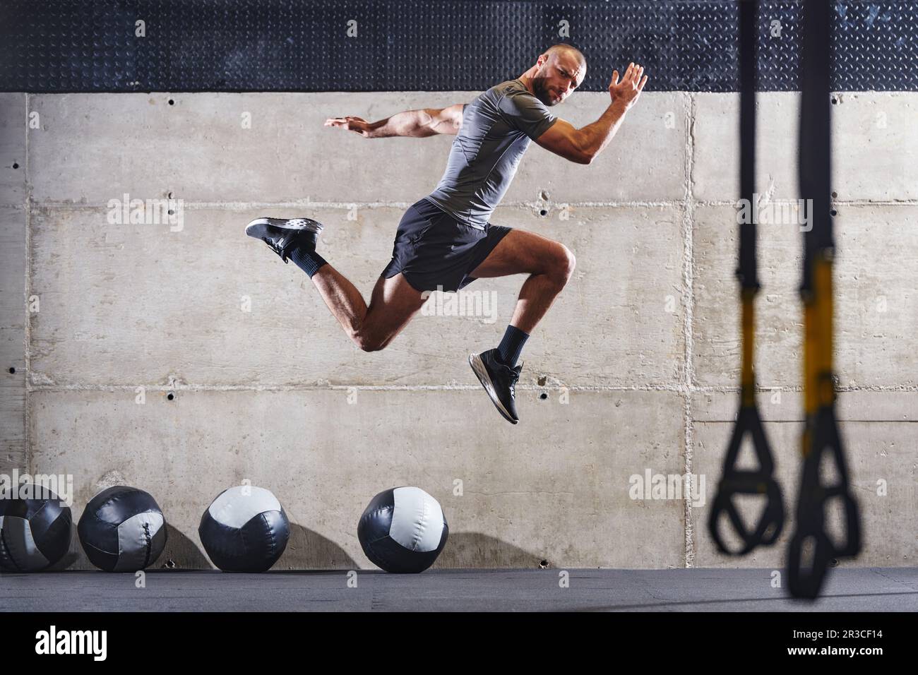 A muscular man captured in air as he jumps in a modern gym, showcasing ...