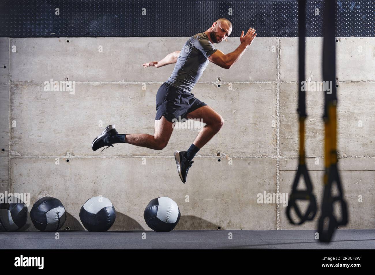A muscular man captured in air as he jumps in a modern gym, showcasing ...