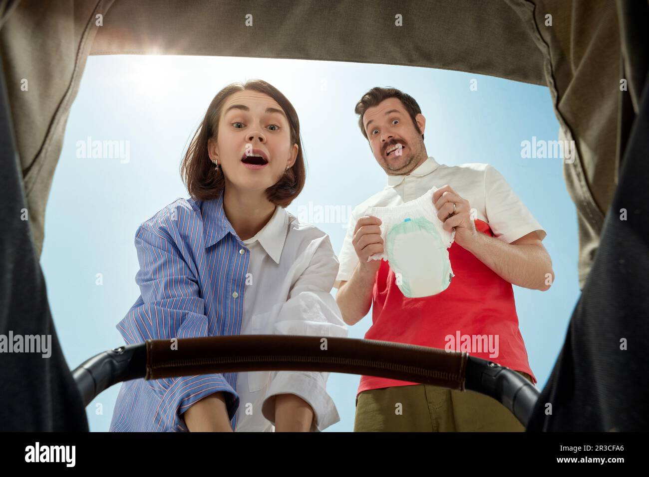Young parents, happy man and woman looking into baby carriage during ...