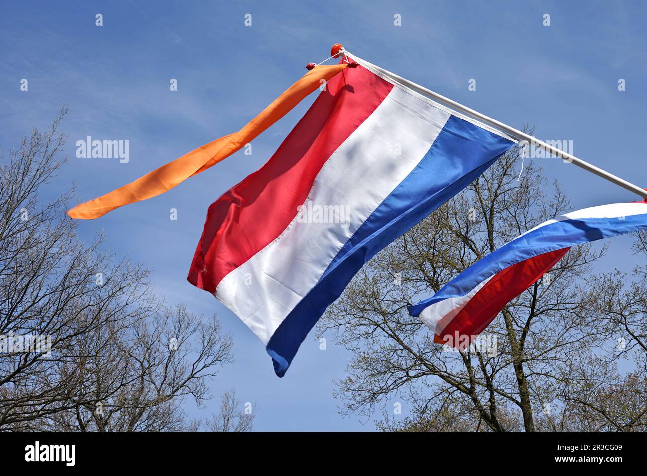 Dutch flags in red, white and blue, waving in the wind, with an orange ...
