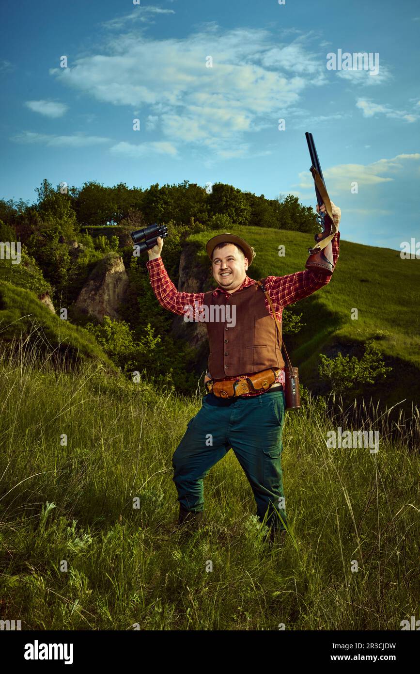 Portrait with happy smiling man, hunter holding weapon and binoculars ...