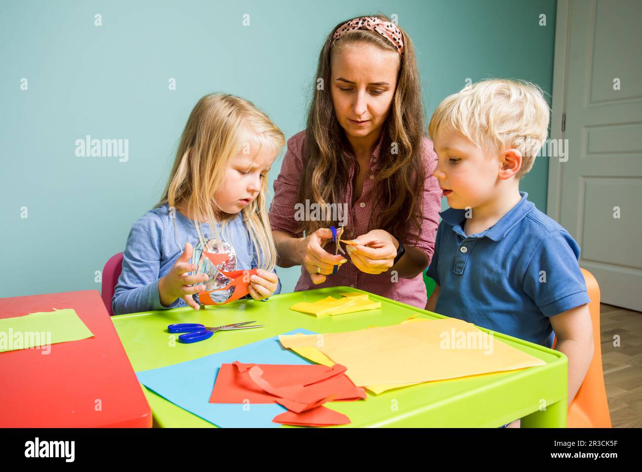 Little kids make a colorful poster with a tutor Stock Photo - Alamy