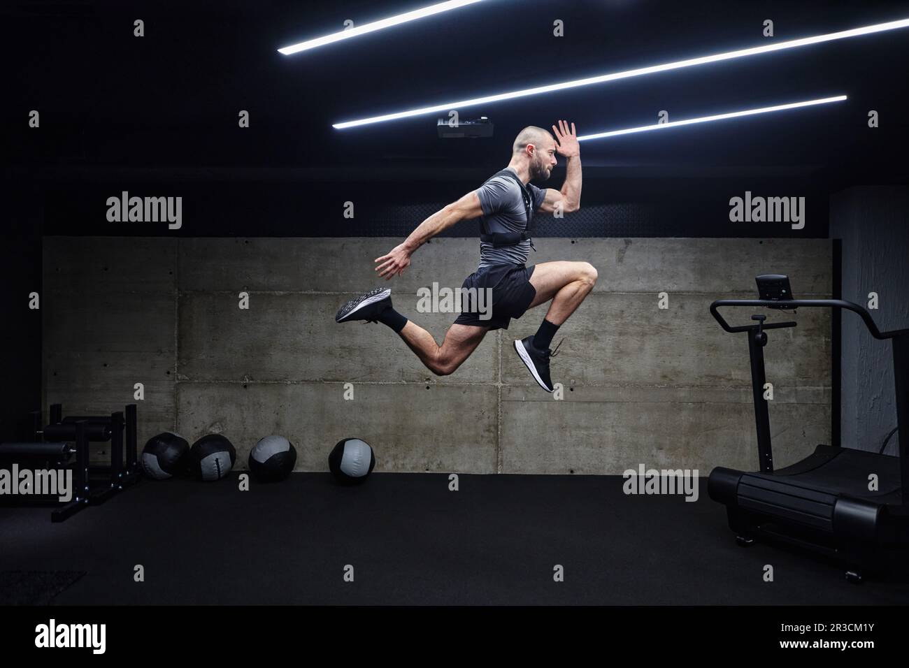 A muscular man captured in air as he jumps in a modern gym, showcasing ...