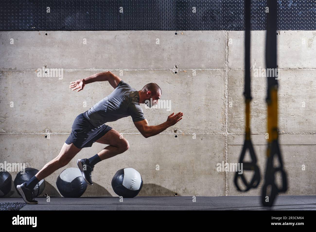 A muscular man captured in air as he jumps in a modern gym, showcasing ...