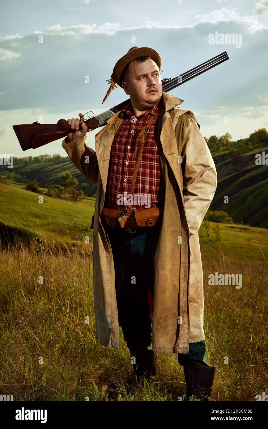 Portrait with experienced hunter wearing checked shirt and hat holding ...