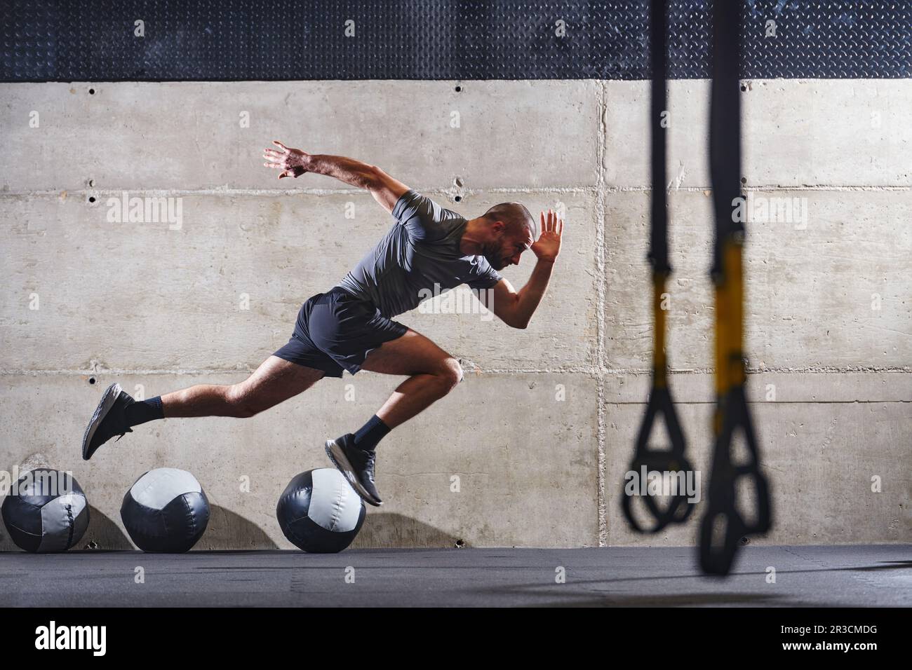 A muscular man captured in air as he jumps in a modern gym, showcasing ...