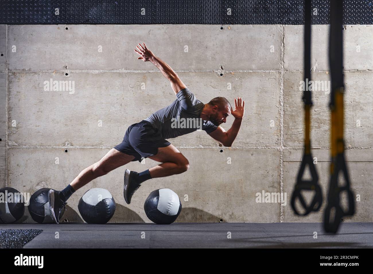 A muscular man captured in air as he jumps in a modern gym, showcasing ...