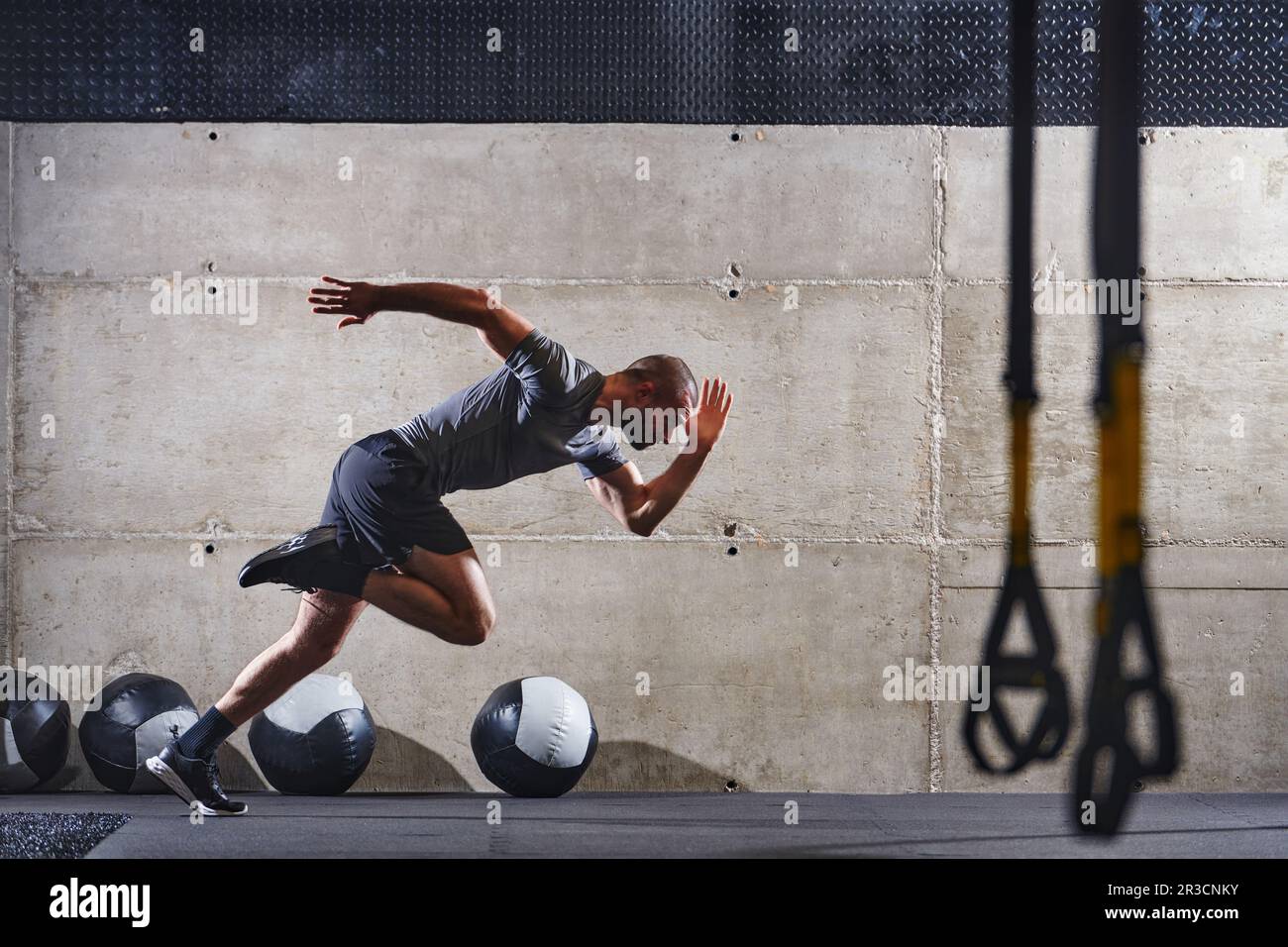 A muscular man captured in air as he jumps in a modern gym, showcasing ...