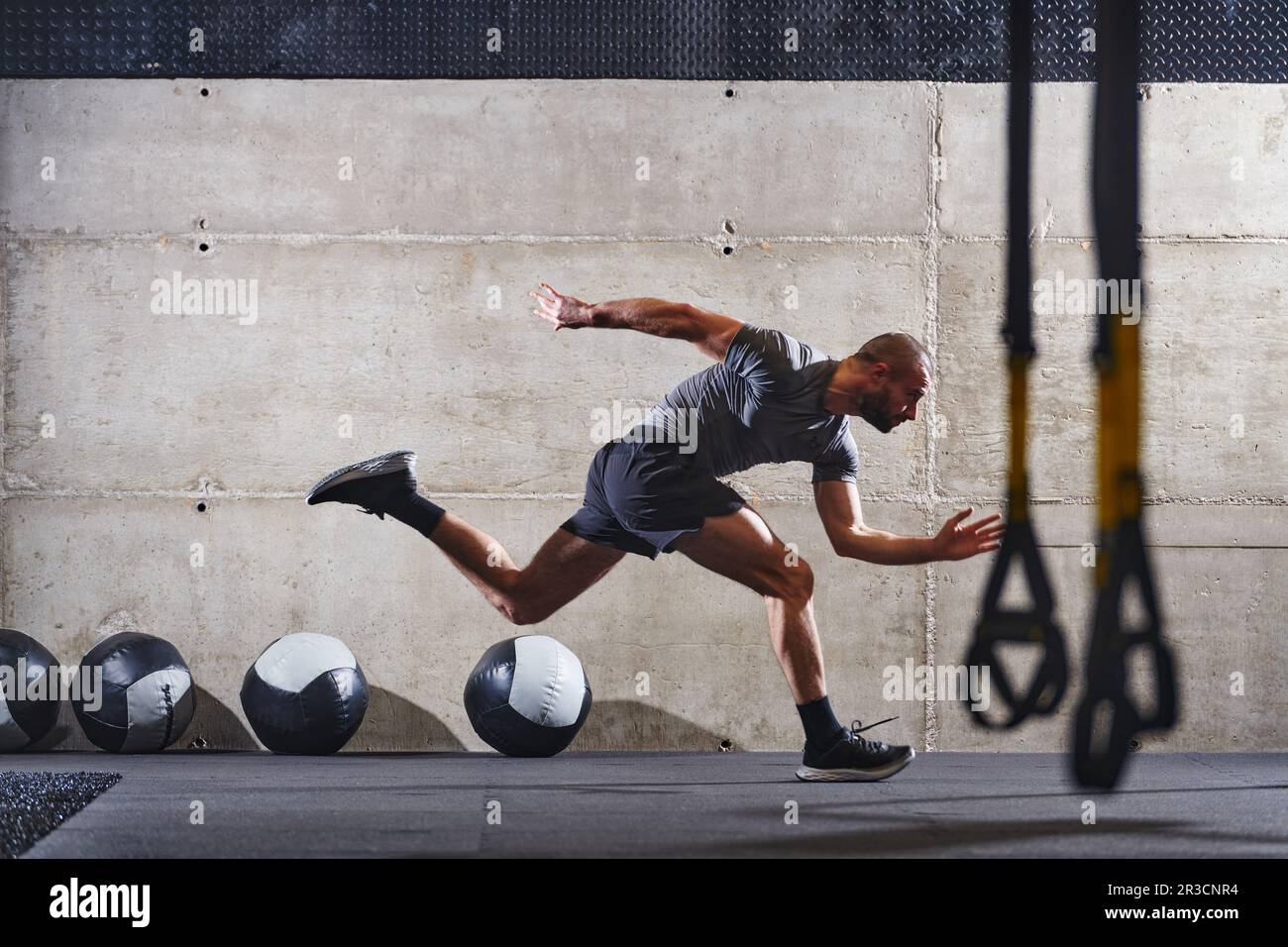 A muscular man captured in air as he jumps in a modern gym, showcasing ...