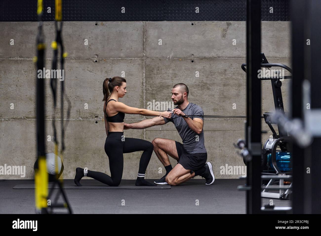 A Muscular Man Assisting A Fit Woman In A Modern Gym As They Engage In Various Body Exercises
