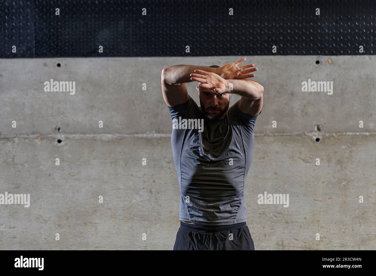 A muscular man working stretching exercises for his arms and body ...