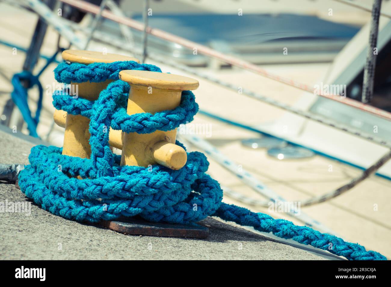 Thick blue rope and yellow bollards on wharf using for anchorage of ...