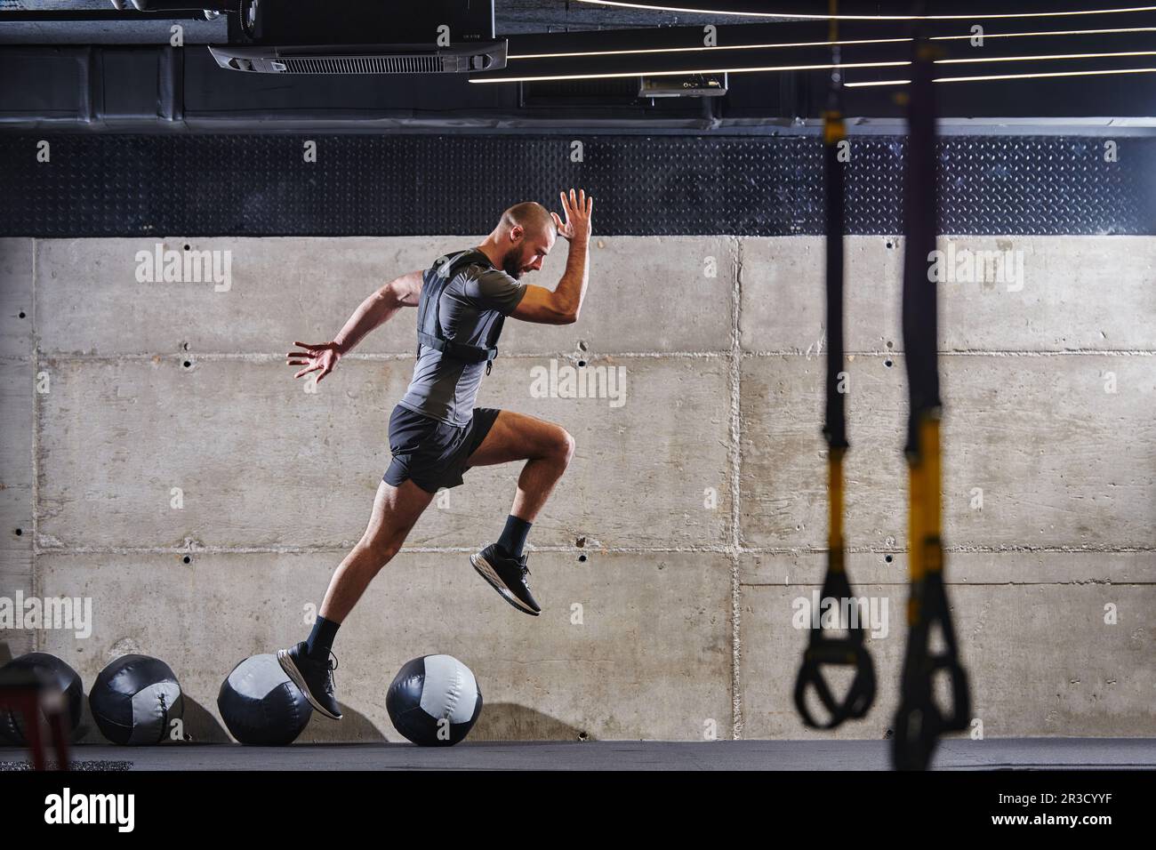 A muscular man captured in air as he jumps in a modern gym, showcasing ...