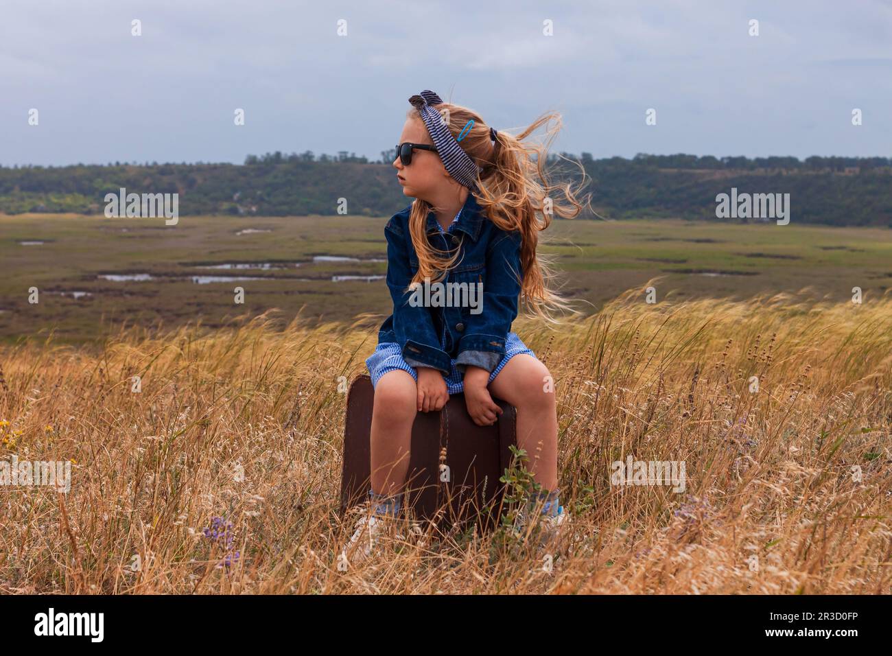 Little Blonde Girl In Denim Jacket Black Sunglasses Blue Dress With Vintage Suitcase In Wild