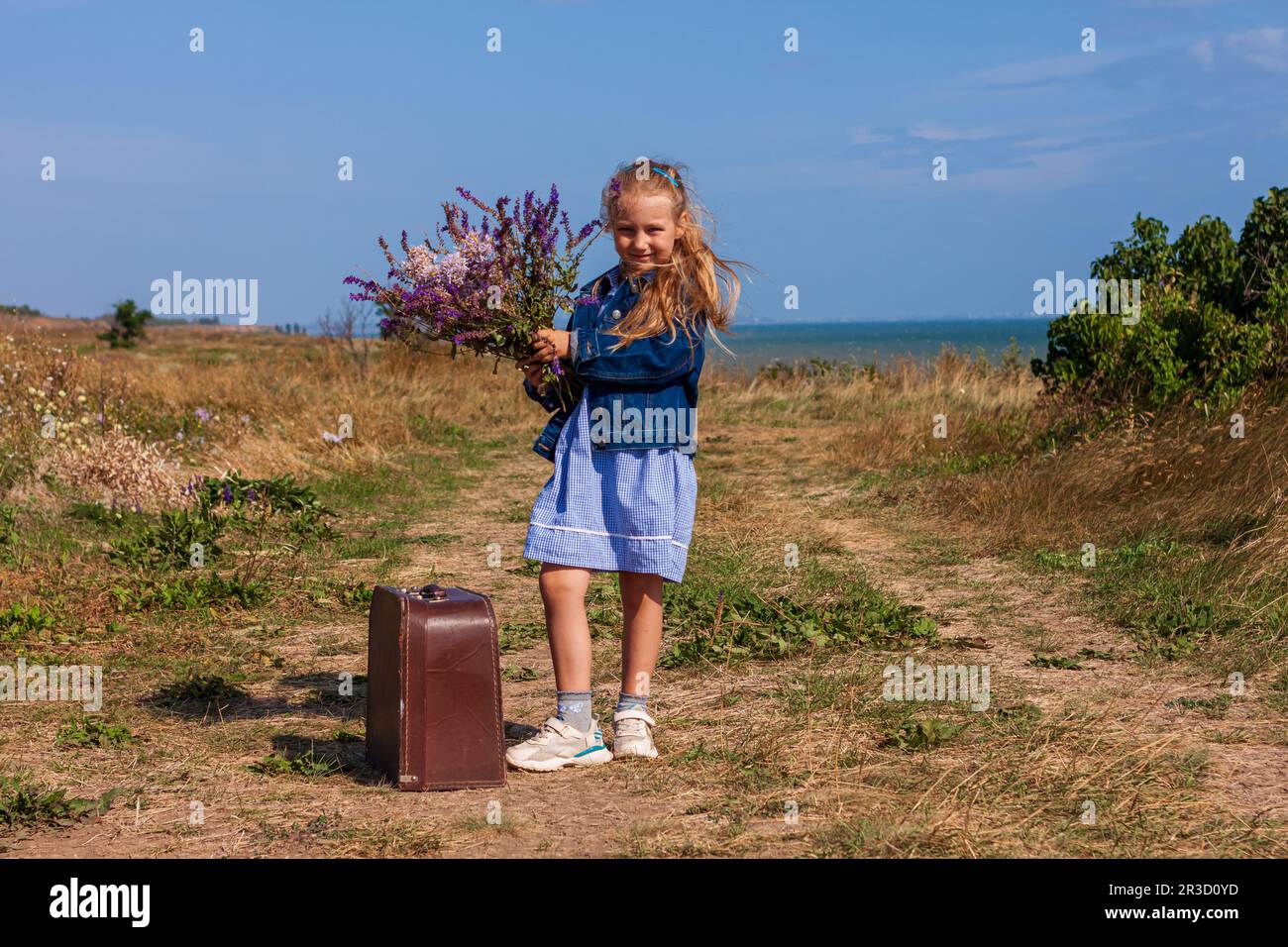 Little Blonde Girl In Denim Jacket Blue Dress With Vintage Suitcase And Flowers Bouquet Off