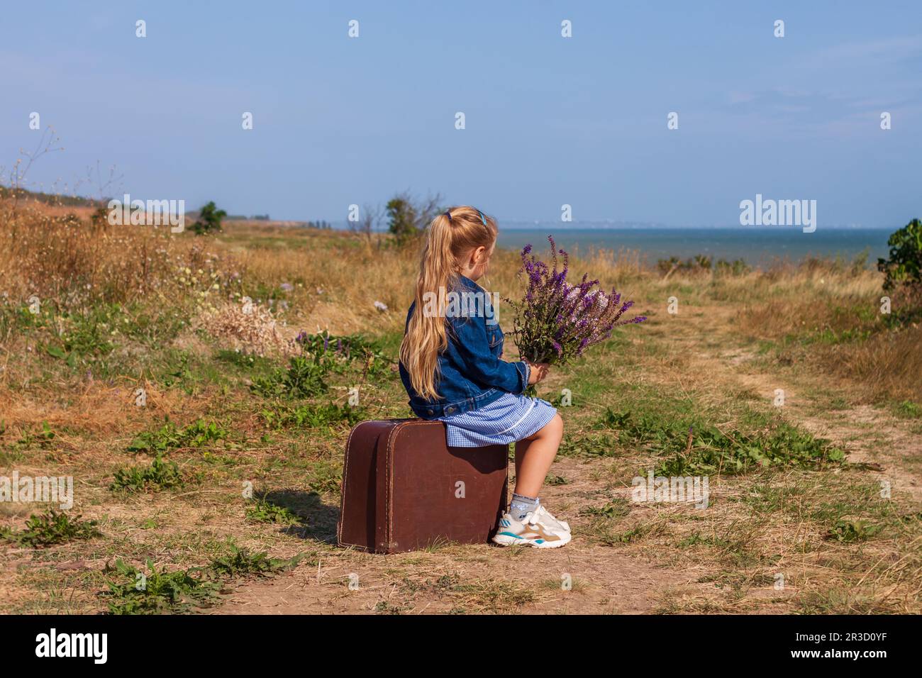 Little Blonde Girl In Denim Jacket Blue Dress With Vintage Suitcase And Flowers Bouquet Off