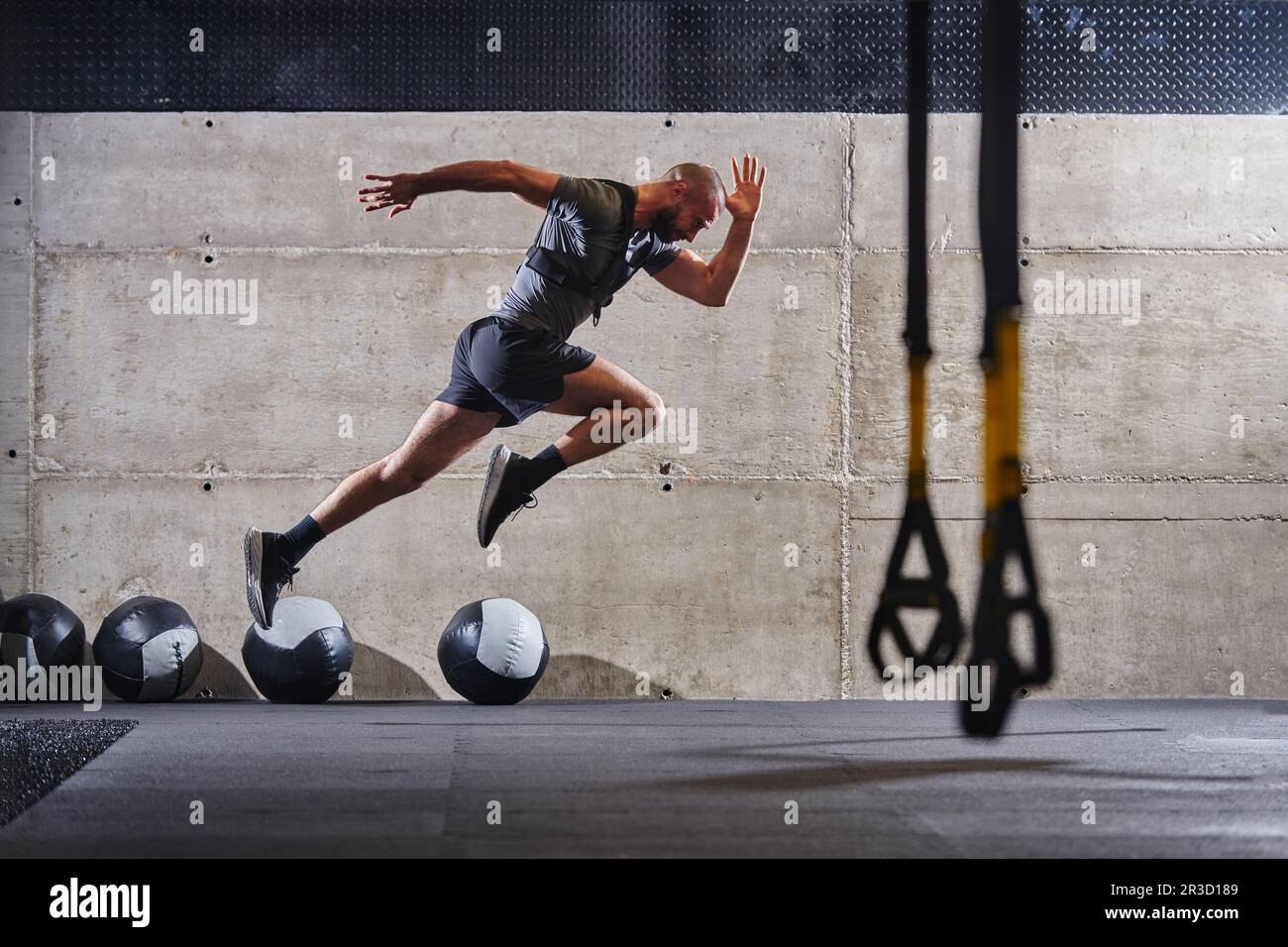 A muscular man captured in air as he jumps in a modern gym, showcasing ...