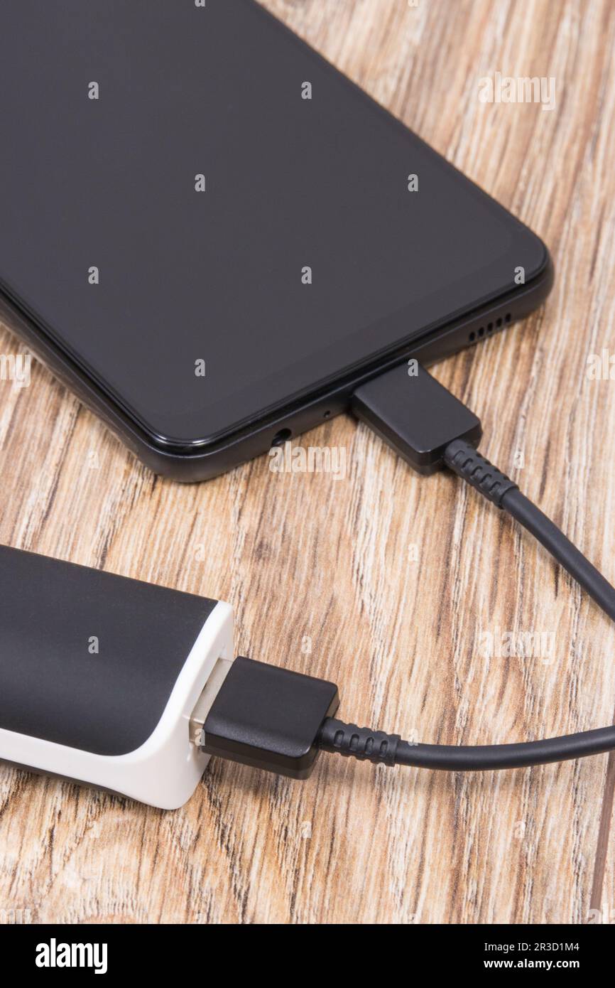 External powerbank using to charge empty battery of black smartphone or ...