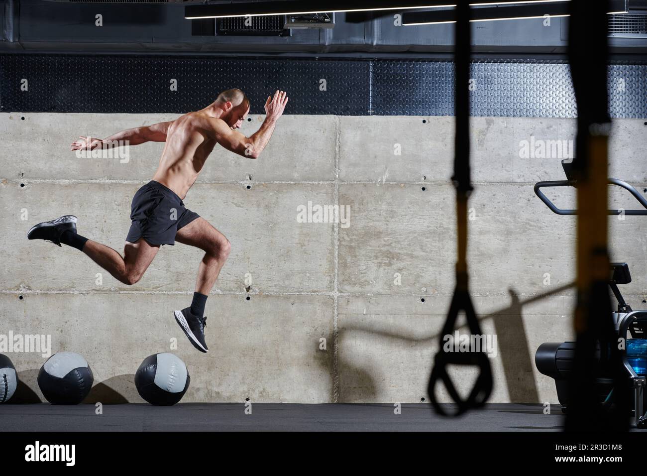 A muscular man captured in air as he jumps in a modern gym, showcasing ...
