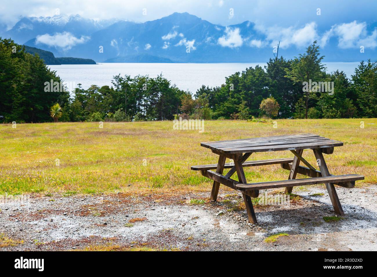 Wooden picnic table overloking scenic Manapouri Lake and mountain range ...
