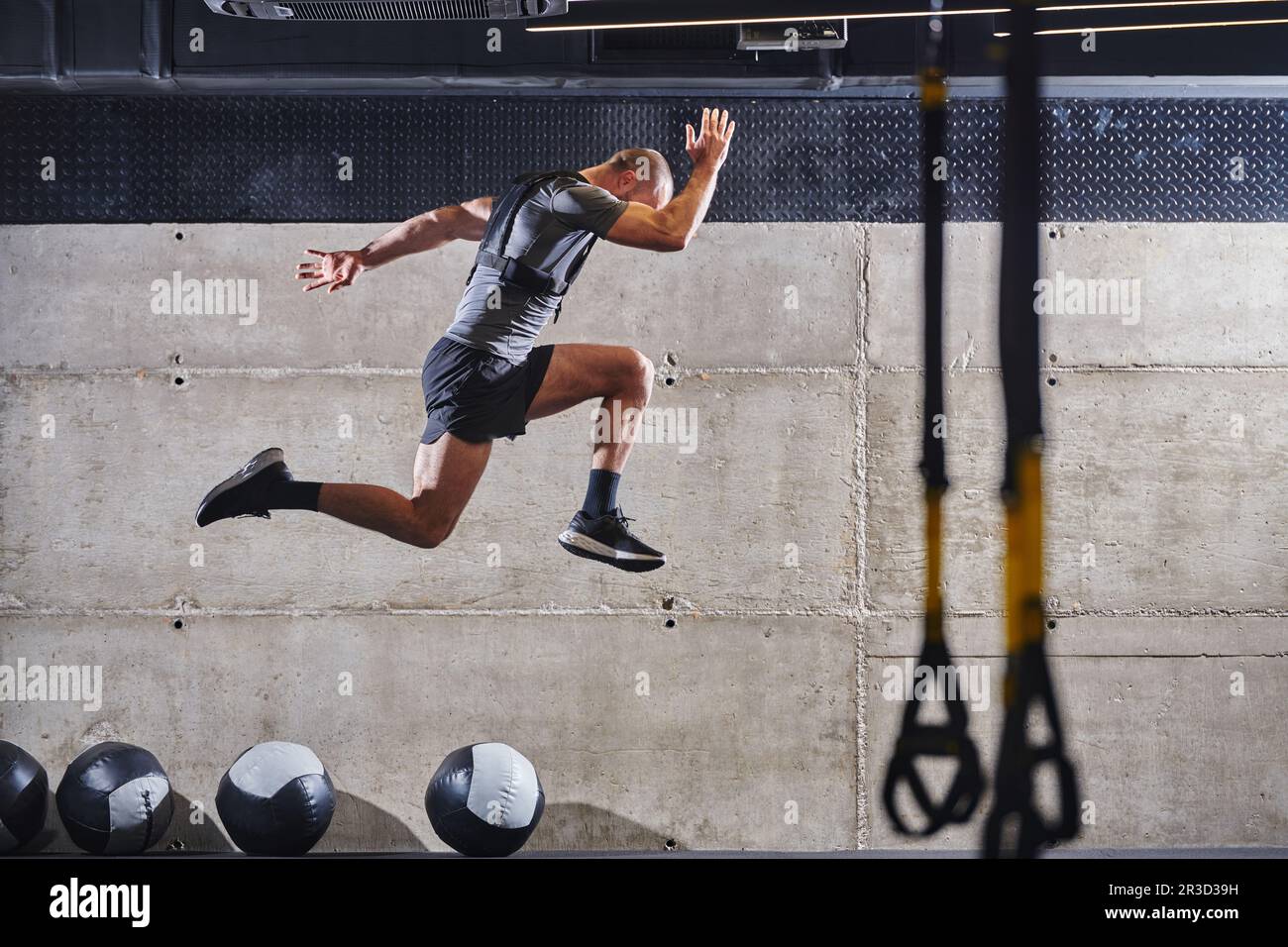 A muscular man captured in air as he jumps in a modern gym, showcasing ...