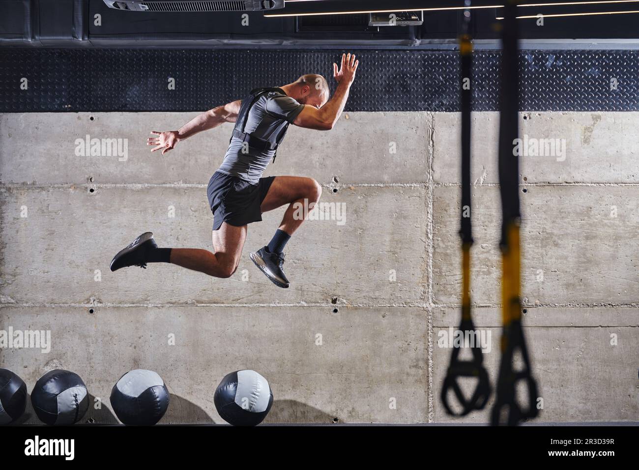 A muscular man captured in air as he jumps in a modern gym, showcasing ...