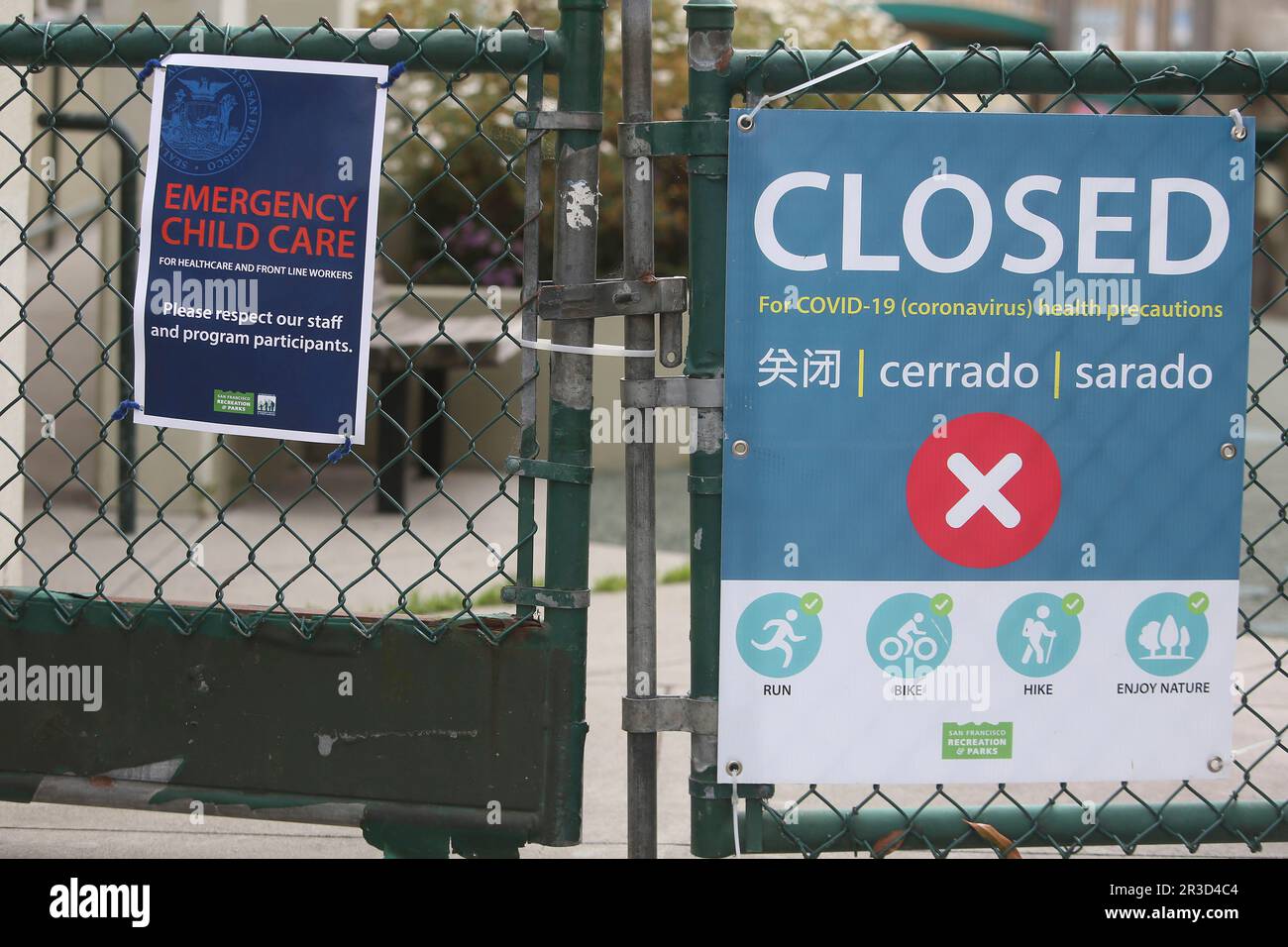 An emergency child care and closed playground signs are seen on a gate ...