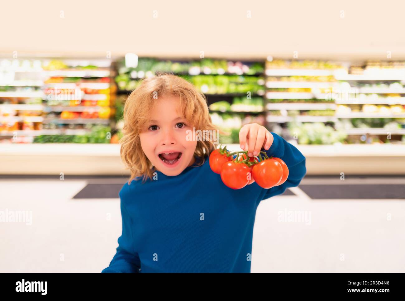 Child with fresh tomato vegetables. Kid choosing food in grocery store ...