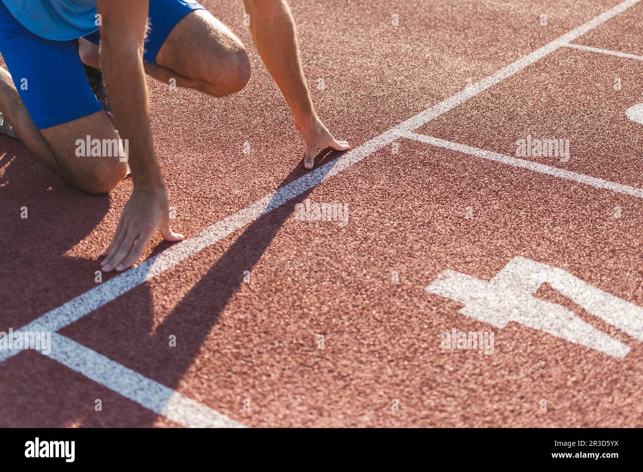 Caucasian male arms and hands on the running track starting line, ready ...