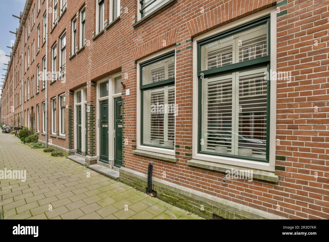 a bricked building with green shutters on the windows and white trim ...