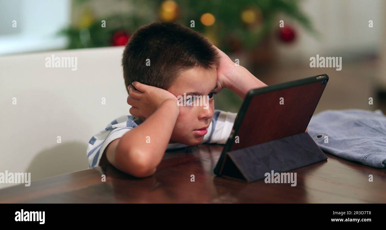 Child hypnotized by tablet device at home. Kid watching cartoon movie ...