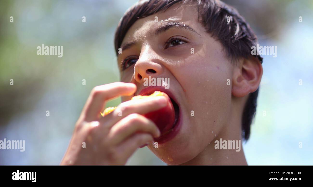 Child eating peach fruit outdoors taking a bite of healthy snack Stock ...