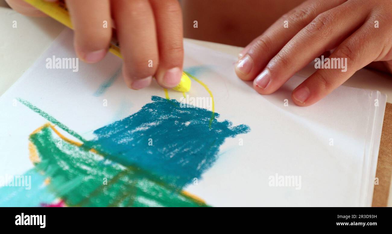 Child hands drawing on paper with crayon. Closeup kid hand draws with ...