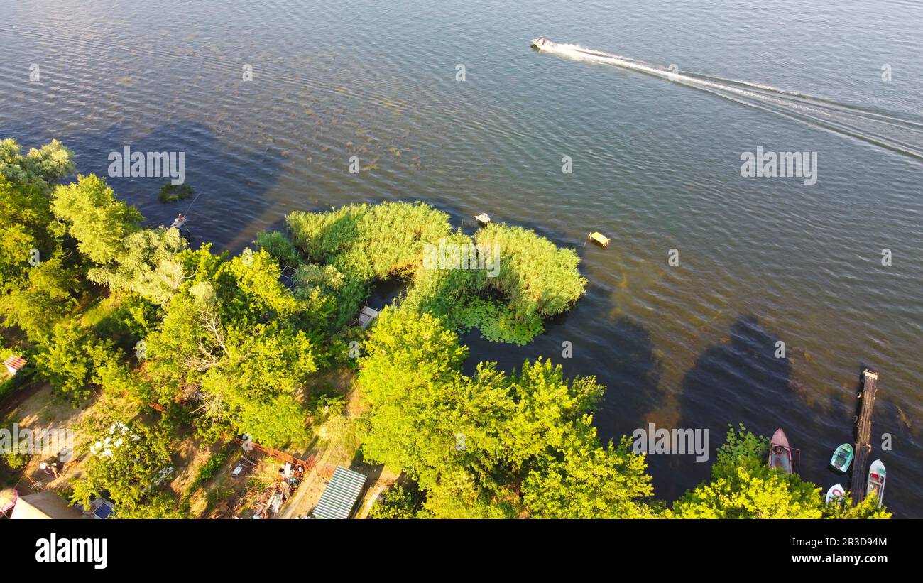 Drone fly over waving river surrounded by local village with various ...