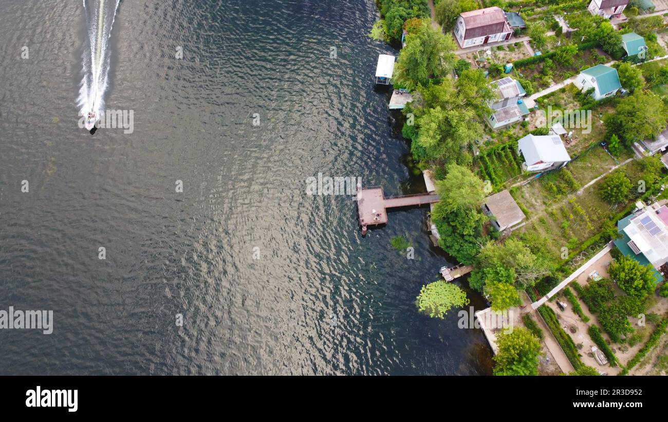 Drone fly over waving river surrounded by local village with various ...