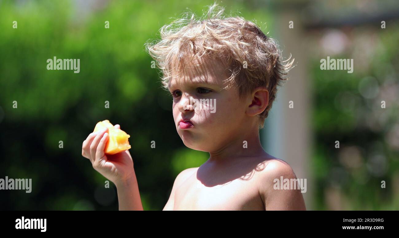 Child boy sniffing outside while chewing fruit Stock Photo - Alamy