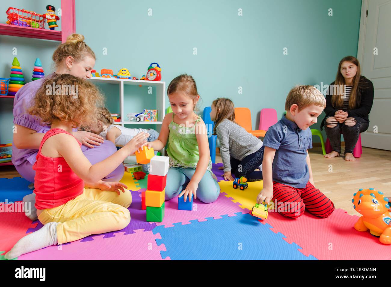 Kids playing together on a colorful mats Stock Photo - Alamy