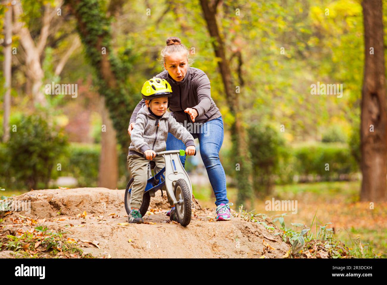 Supportive mom encourages boy to ride down the hill Stock Photo - Alamy