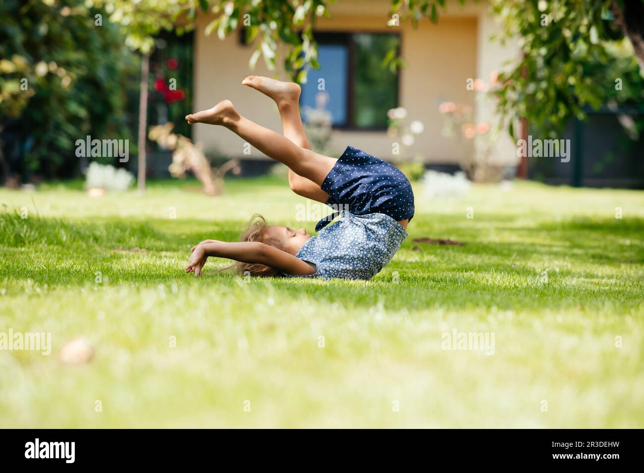 Active little girl makes a somersault on the backyard Stock Photo - Alamy