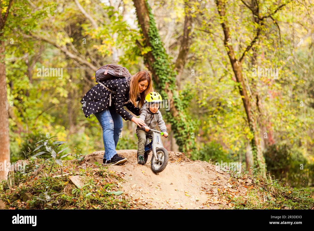 Supportive mom encourages boy to ride down the hill Stock Photo - Alamy