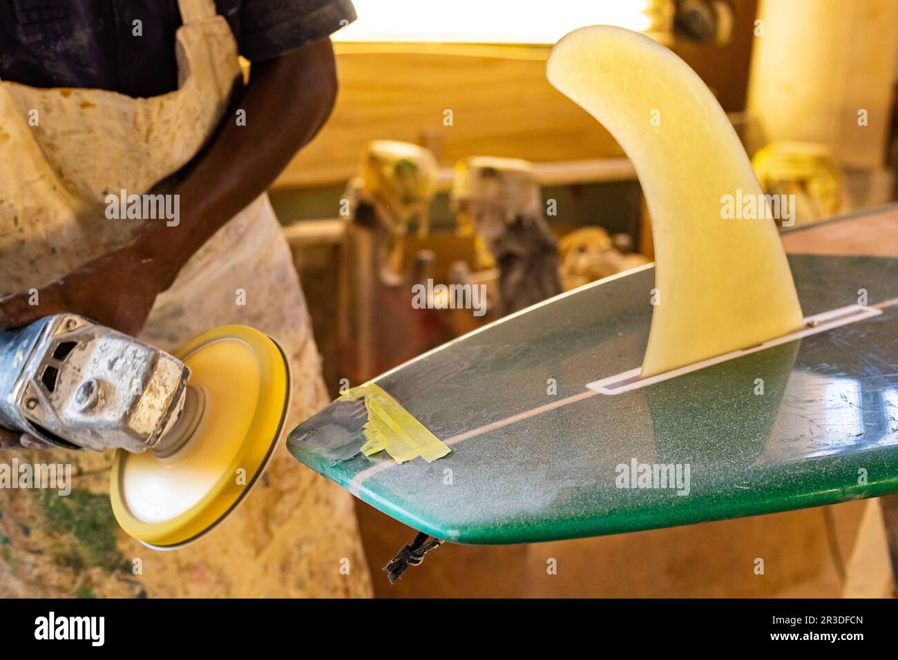 An African Craftsman surfboard Shaper working in a repair workshop ...