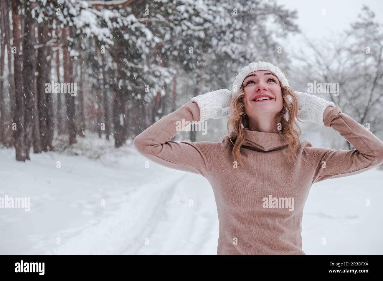 Christmas, holidays and season concept. Young happy woman blowing snow in the winter forest ...