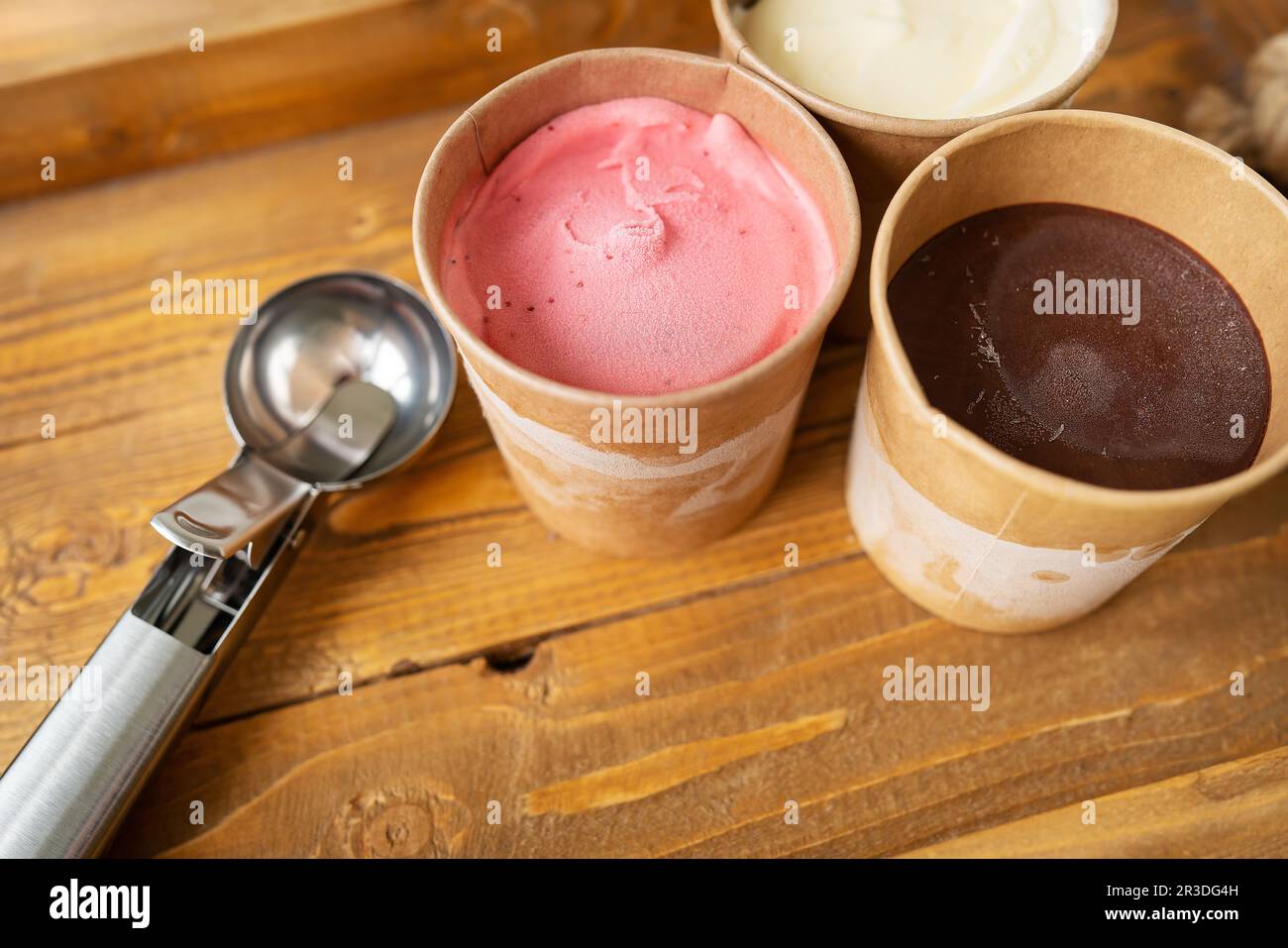 Ice cream in a box with different flavors stand on a wooden tray along ...
