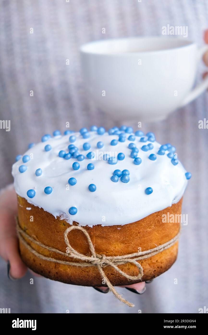 Hands hold Easter cake with white topping and blue sprinkles. Woman ...