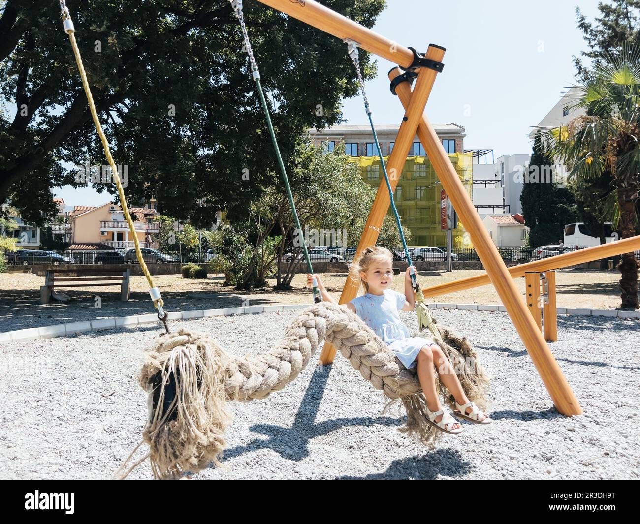 Little girl swings on a swing in the form of a braid on the playground Stock Photo - Alamy