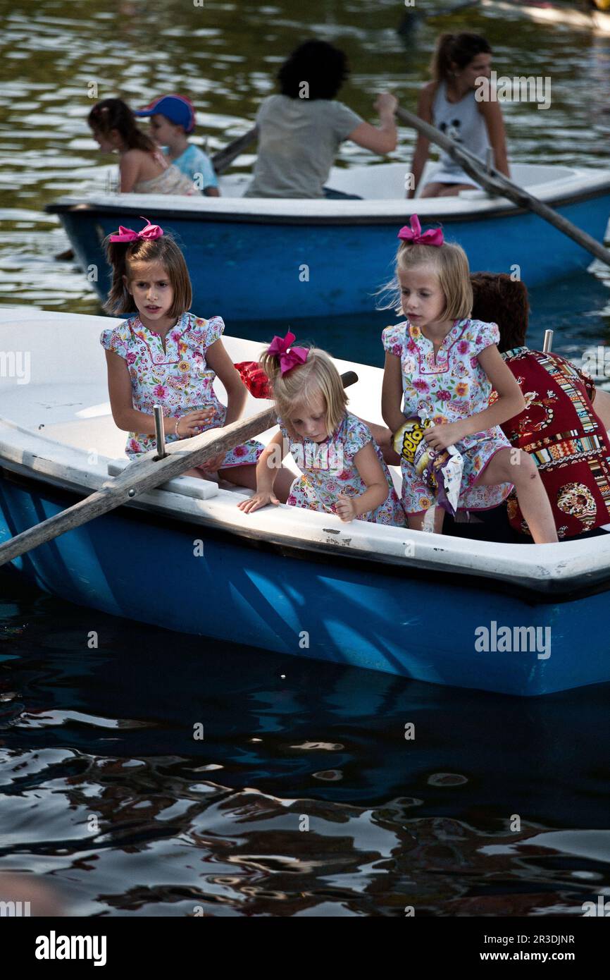 Three sisters, dressed alike, feeding the fish at the pond of the Buen ...