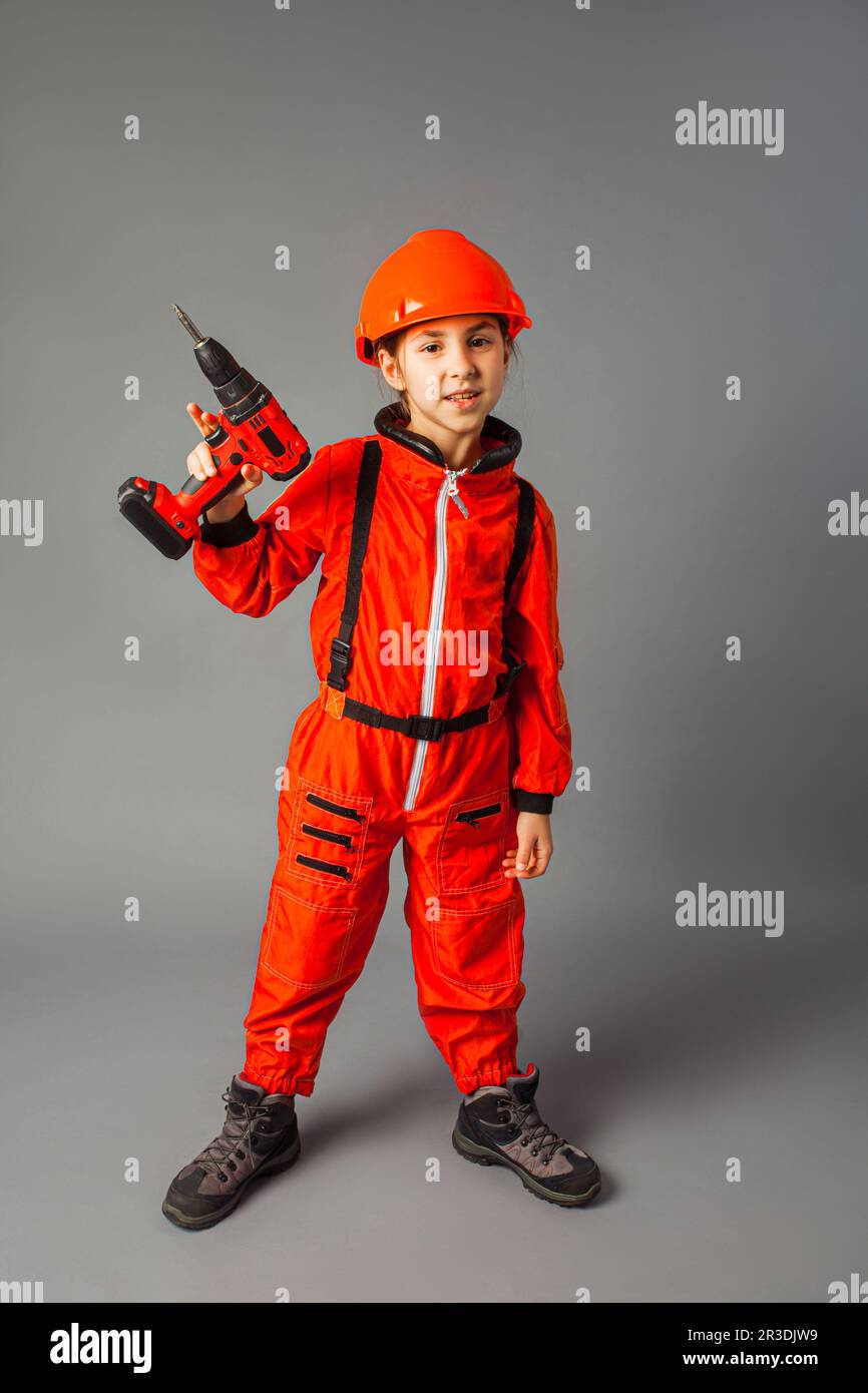 The little girl dressed in a red engineering uniform is holding a ...