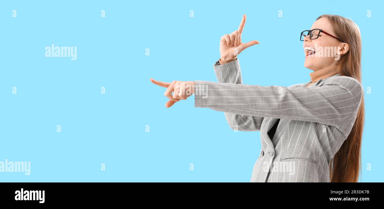 Laughing young businesswoman showing loser gesture on light blue ...